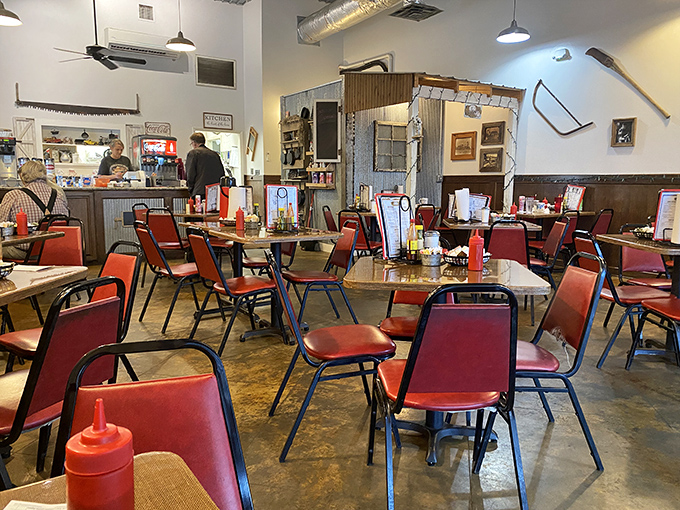 Red chairs await hungry patrons in a dining room where conversations flow as freely as the coffee. No designer needed—just honest comfort. 