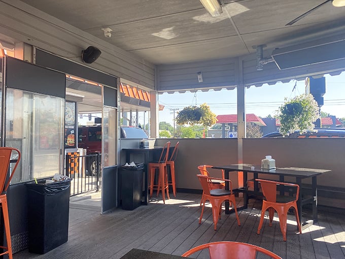 Orange chairs await beneath hanging flower baskets, creating that perfect "third place" between home and work where memories are made over milkshakes. 