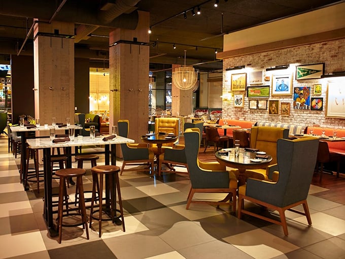 Where rustic meets refined – colorful chairs pop against checkerboard floors while exposed brick walls showcase local art. Comfort disguised as elegance.