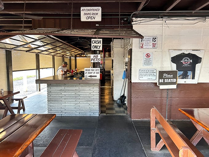 No-frills dining at its finest—picnic tables, wooden benches, and a "Please Be Seated" sign that might as well read "Prepare for Deliciousness."