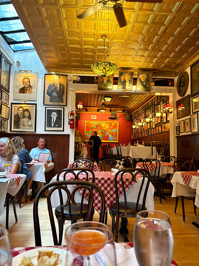 Opera legends watch over diners from every wall, while the golden tin ceiling reflects warm light across red-checkered tables—dinner with a side of history.