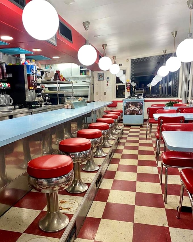 Red stools lined up like loyal soldiers, ready for the breakfast brigade. This checkerboard floor has witnessed countless coffee refills.