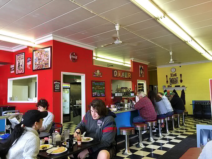 Classic diner aesthetics done right: red walls, checkered floors, and counter seating where breakfast dreams come true.