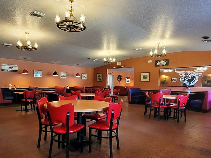 Red chairs pop against orange walls in this no-frills dining room. The wagon wheel chandeliers aren't trying to impress Architectural Digest—they're saving their energy for your taste buds.