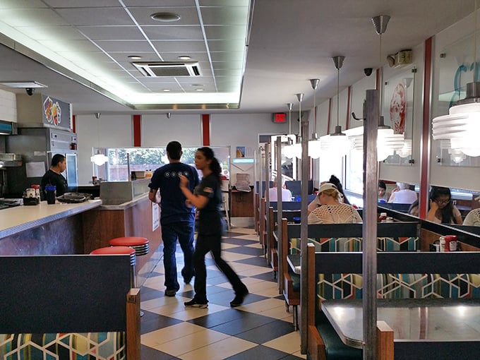 Classic black and white checkered floors set the stage for culinary theater, where servers dance between booths delivering plates that could make a food photographer weep.