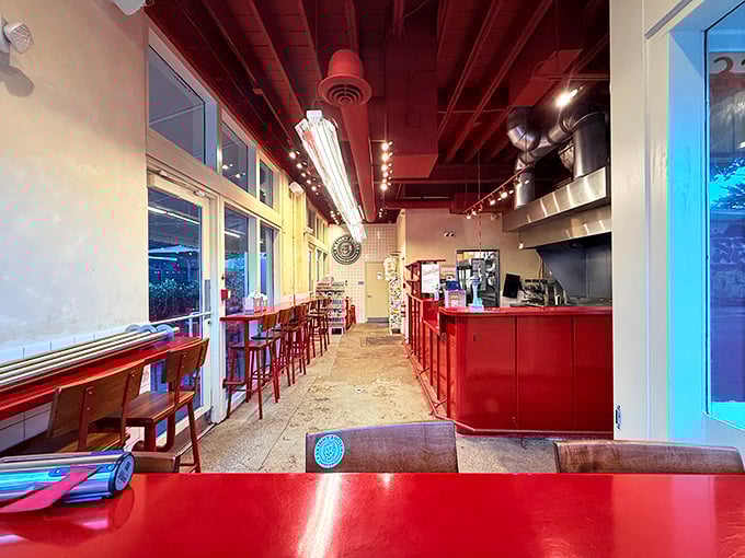 Minimalist design with maximum impact—red accents and an open kitchen where burger artistry happens before your eyes.