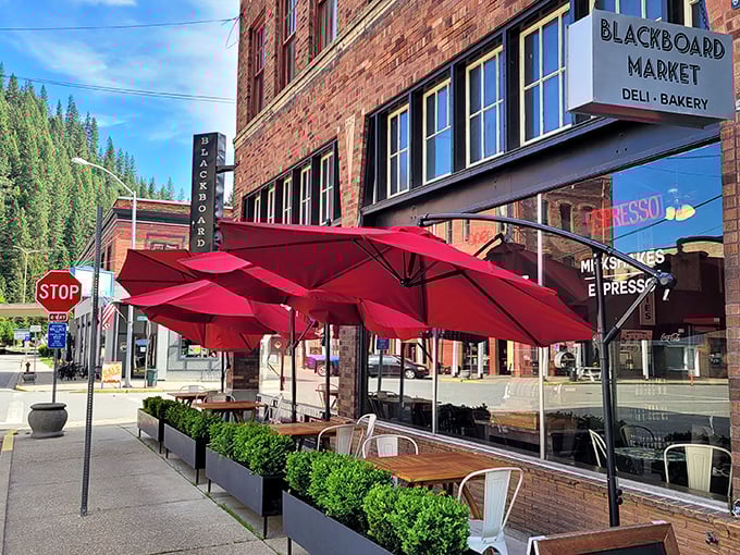 The Blackboard Café's crimson umbrellas beckon like old friends, promising huckleberry pancakes and local gossip served with equal enthusiasm under the watchful gaze of pine-covered hills.