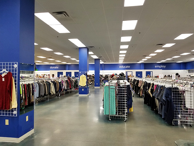 A thrifter's paradise stretches before you with organized racks and the Goodwill mantra—donate, educate, employ—guiding your shopping journey.