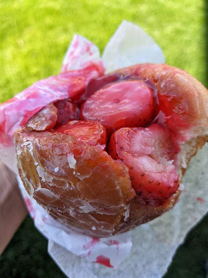 Behold the holy grail of donuts: fresh strawberries bursting from a perfectly glazed vessel. This isn't just breakfast—it's a California dream wrapped in paper.