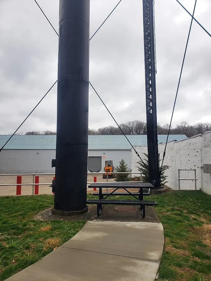 A humble picnic table sits beneath the mighty bottle, perfect for contemplating life's big questions, like "Why isn't all architecture this deliciously literal?"