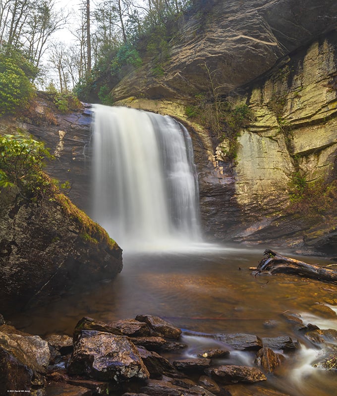 The waterfall's silky white veil contrasts dramatically with the golden-hued rocks, creating what photographers call "the money shot" – no filter required!