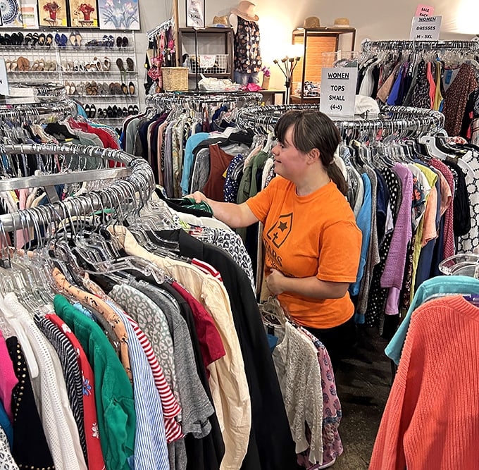 A volunteer navigates the meticulously organized clothing forest—where fashion finds from yesterday wait for tomorrow's closets.