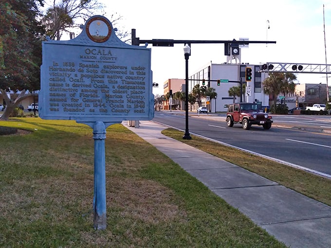 A blue historical marker tells Ocala's story while modern life buzzes around it—past and present in perfect harmony.