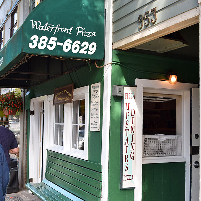 That green awning signals serious business – the kind where locals queue happily for waterfront pizza perfection.