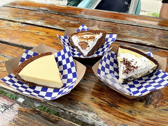 Pie trinity on blue-checkered paper – the holy communion of desserts. Each slice promises a different path to culinary enlightenment.