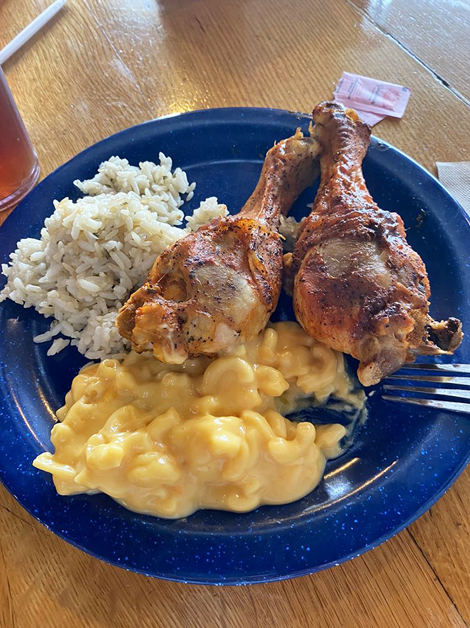 Golden fried chicken legs perch atop creamy mac and cheese and rice—a holy trinity of Southern comfort that makes diets weep and taste buds rejoice.