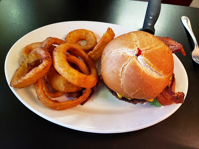 This burger isn't just wearing bacon like an accessory—it's a full commitment. Those onion rings could double as delicious golden bracelets.