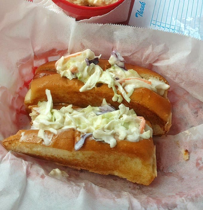The star attraction in all its glory—a hot dog transformed into culinary poetry with creamy coleslaw piled high enough to require strategic first-bite planning.