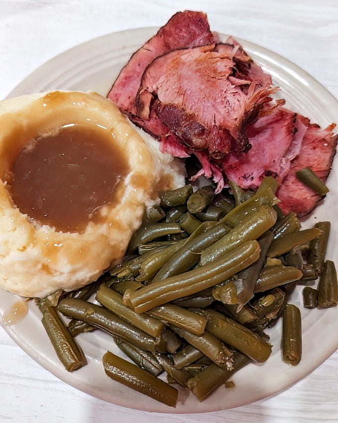 This isn't just baked ham—it's a masterclass in comfort food geometry: the perfect triangle of meat, the circle of mashed potatoes, the straight lines of green beans.