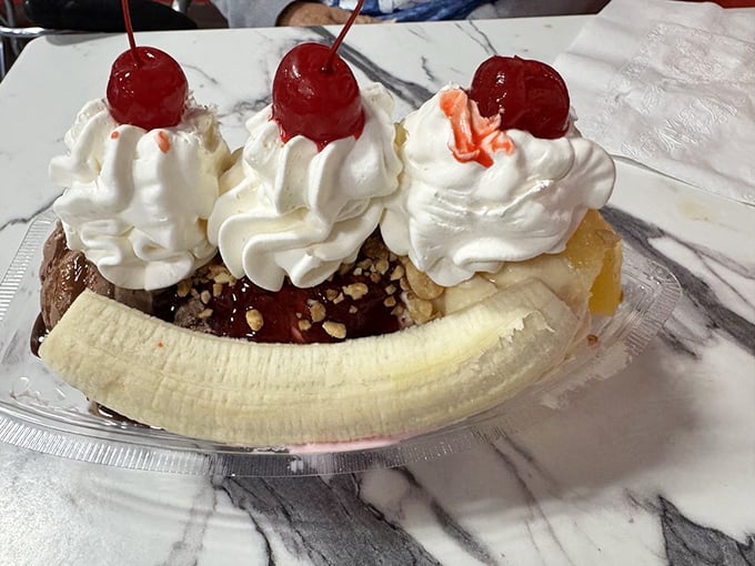 Behold the Monster Banana Split in all its glory—three scoops nestled in a banana boat, crowned with whipped cream and cherries like royalty.