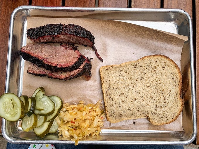 Behold the brisket in all its glory—sporting a bark so perfect it deserves its own hall of fame induction, alongside pickles that cut through the richness like a well-timed joke.