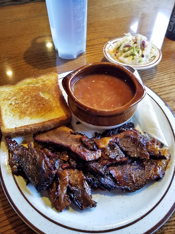 Behold the brisket in all its glory – tender slices sporting that coveted pink smoke ring, served with Texas toast and coleslaw that knows its supporting role.