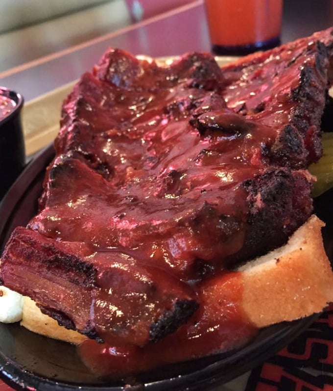 These beef ribs aren't just dinner; they're prehistoric monuments to smoke and time, glistening with sauce and demanding both hands and your complete attention.
