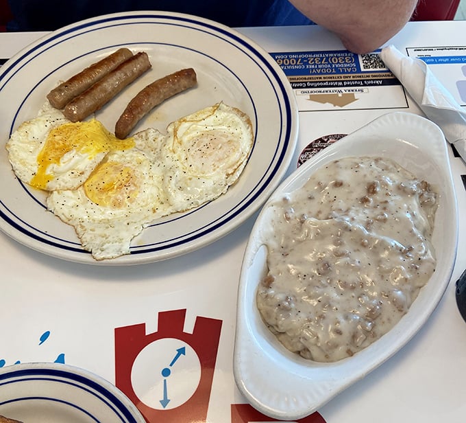 Behold the star attraction – creamy sausage gravy cascading over fluffy biscuits, with eggs and sausage links playing delicious supporting roles.