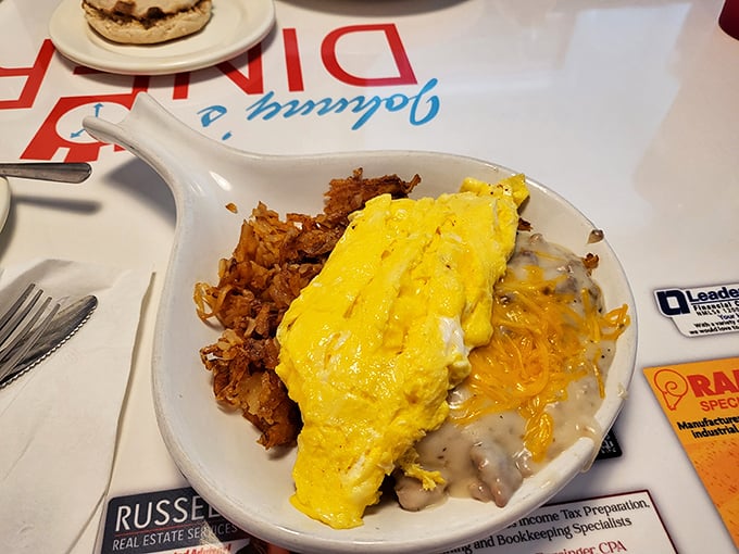 Breakfast alchemy at its finest – a golden omelet spills over crispy hash browns with a side of gravy that would make your grandmother jealous.