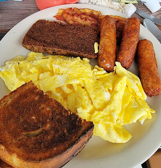 Breakfast perfection on a plate – scrapple, sausage links, and eggs scrambled just right, with toast that's actually worthy of the calories.