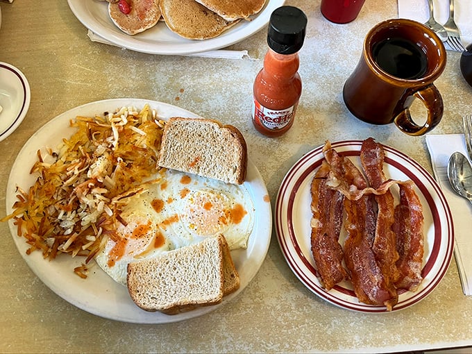 Breakfast perfection on a plate: eggs with that ideal runny yolk, hash browns with the golden crisp edge, and bacon that snaps just right.
