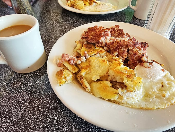 Behold the breakfast of champions: home fries crisped to perfection, eggs sunny-side up, and what appears to be ham—a holy trinity of morning delights.