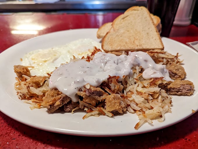 Behold the country breakfast in all its glory—crispy hash browns smothered in gravy, eggs sunny-side up, and toast standing by for yolk-sopping duty.