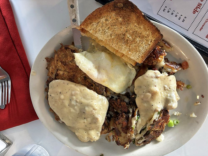 Behold the country breakfast in all its glory—crispy hash browns, eggs, and gravy forming a holy trinity of morning satisfaction.