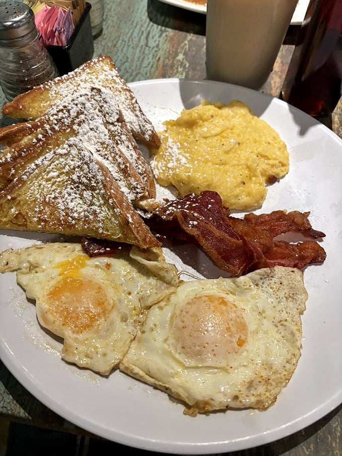 French toast dusted with powdered sugar, perfectly fried eggs, and bacon that knows its job—this is morning done right.