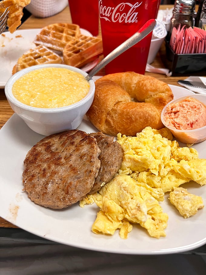 Breakfast nirvana on a plate: fluffy scrambled eggs, sausage patty, grits, and a croissant that would make a French baker nod in approval.