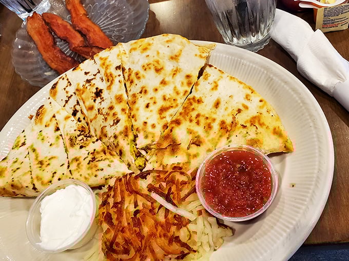 Behold the legendary breakfast quesadilla in its natural habitat—golden-brown, perfectly sectioned, with salsa and sour cream standing by like faithful companions.
