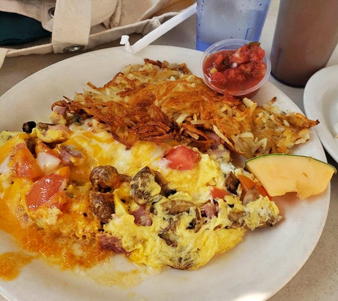 This isn't just an omelet – it's a masterpiece of morning engineering with perfectly crisped hash browns that make you question all other potato preparations.