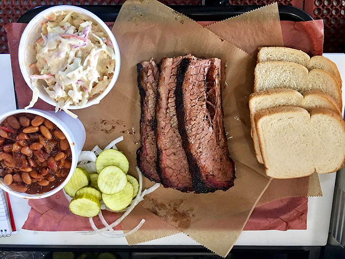 Behold the holy trinity of barbecue perfection – brisket with that telltale smoke ring, beans that didn't come from any can, and slaw for that essential crunch.