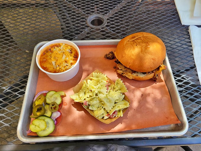 The holy trinity of BBQ perfection: a sandwich that demands two hands, mac and cheese that's actually cheesy, and house-made pickles for that zingy contrast.