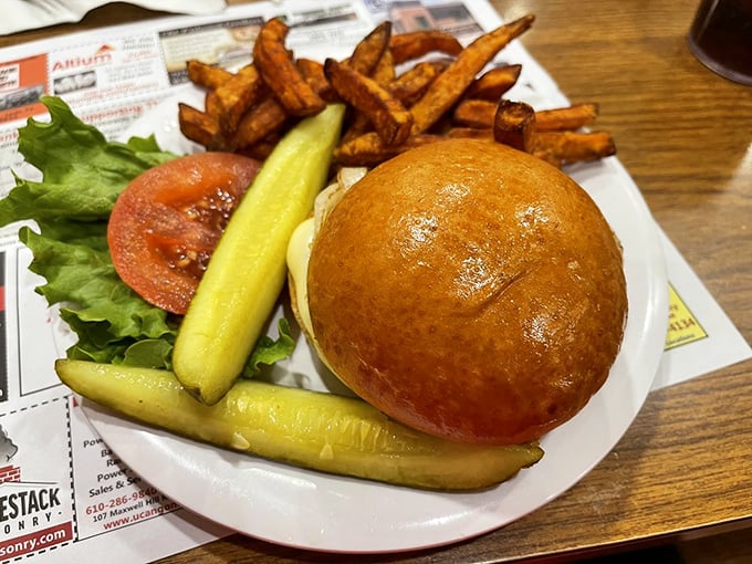 This isn't just a burger—it's a masterclass in simplicity, where a golden brioche bun cradles fresh toppings and those sweet potato fries deserve their own fan club.