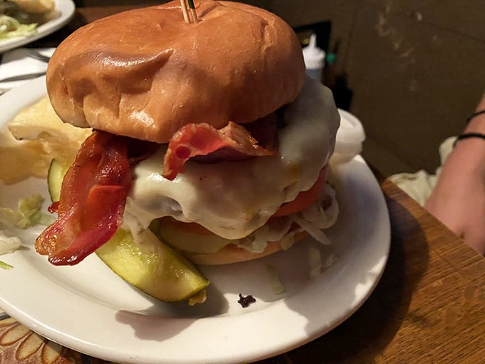 This isn't just a burger; it's architecture. The melted cheese cascades like lava while bacon stands guard over this towering masterpiece.