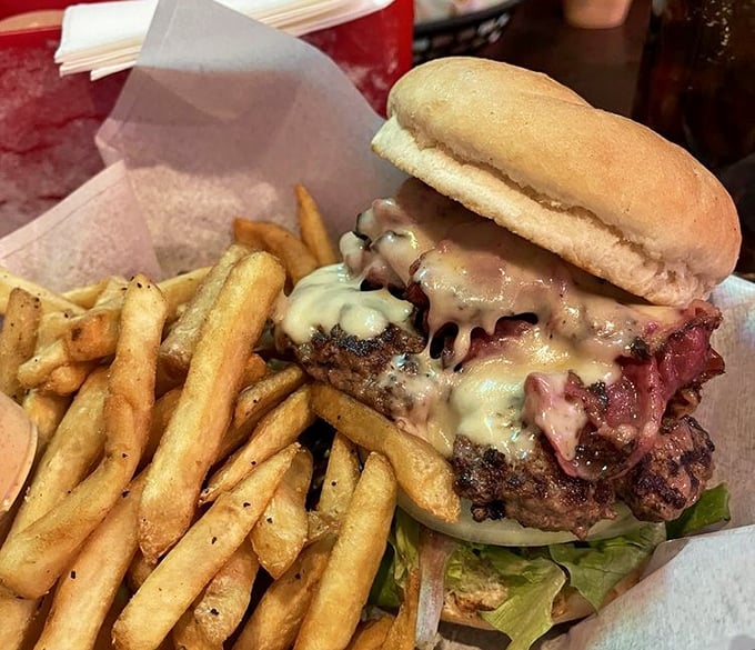This isn't just a burger – it's architecture. Melted cheese cascades over perfectly charred beef with hand-cut fries standing at attention nearby.