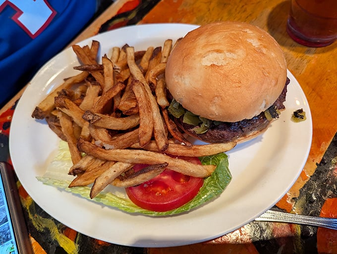 The burger arrives like a savory monument to simplicity done right—hand-cut fries standing guard beside the star attraction.