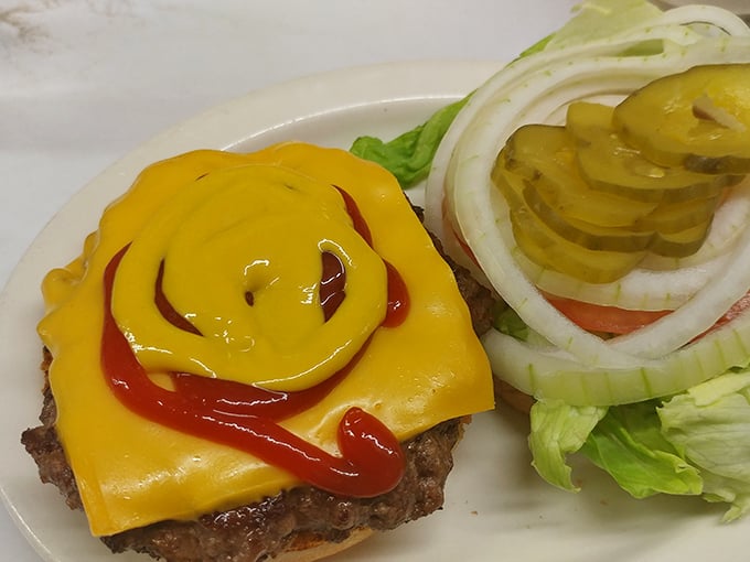 The cheeseburger arrives like a work of art for the everyman—melted American cheese cascading over a hand-formed patty with that perfect griddle char.