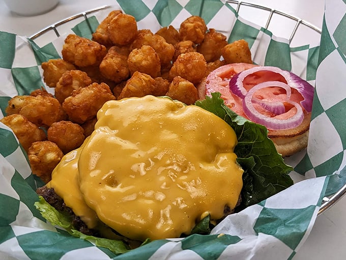 This isn't just a cheeseburger; it's edible architecture – a golden cheese blanket cascading over a perfectly seared patty alongside crispy tater tots.