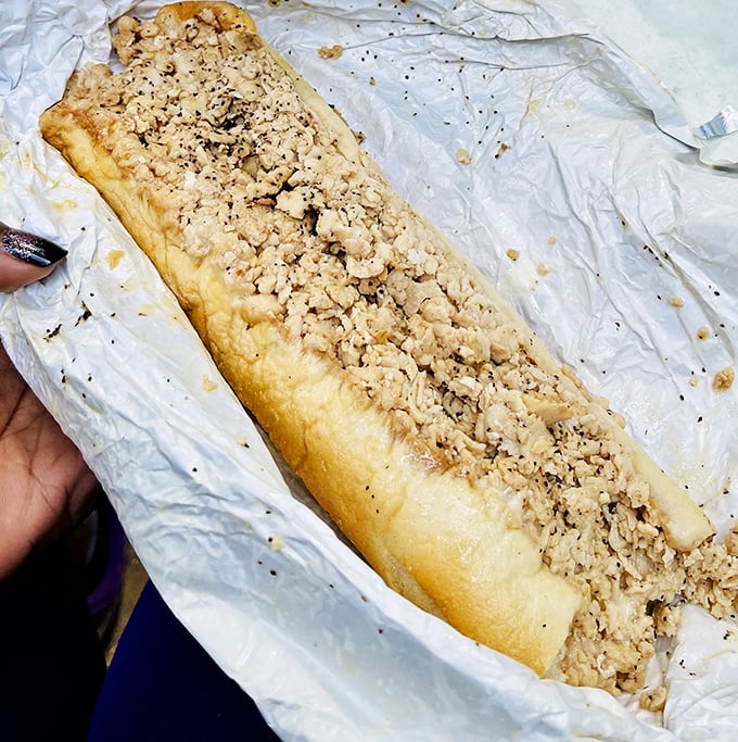 Behold the chicken cheesesteak in its natural habitat – wrapped in paper, perfectly chopped, and ready to make you question why you've eaten anything else.