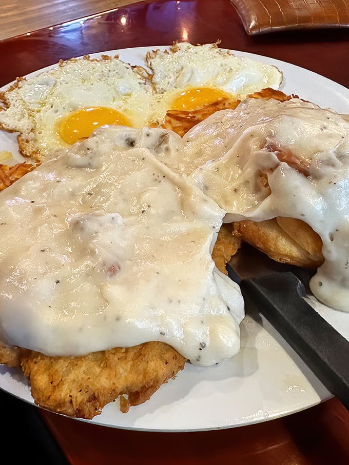 Behold the star of the show! Chicken fried steak smothered in peppery gravy with sunny-side-up eggs – breakfast nirvana on a plate.