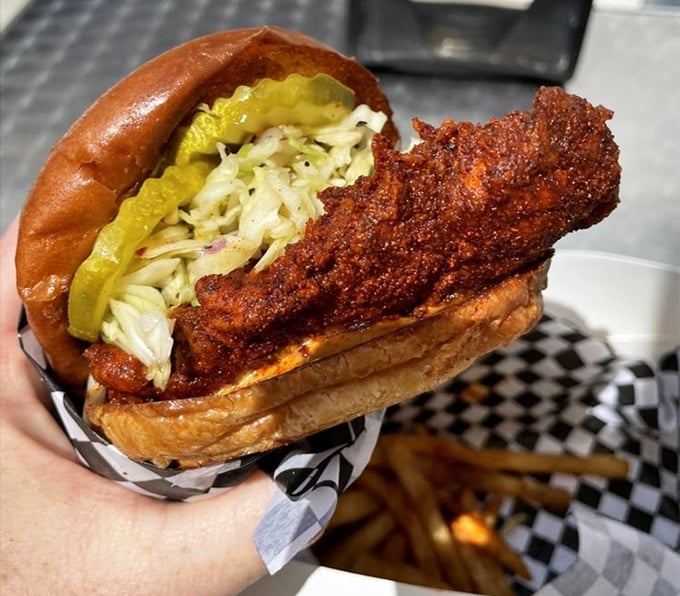 Behold the sandwich that launches a thousand cravings—crispy, fiery chicken nestled with cooling slaw and pickles between a pillowy bun. Poetry in sandwich form.