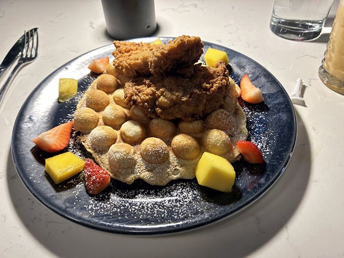 Brunch reimagined: Crispy fried chicken perched atop golden bubble waffles with fresh fruit—a dish that makes morning people out of night owls.